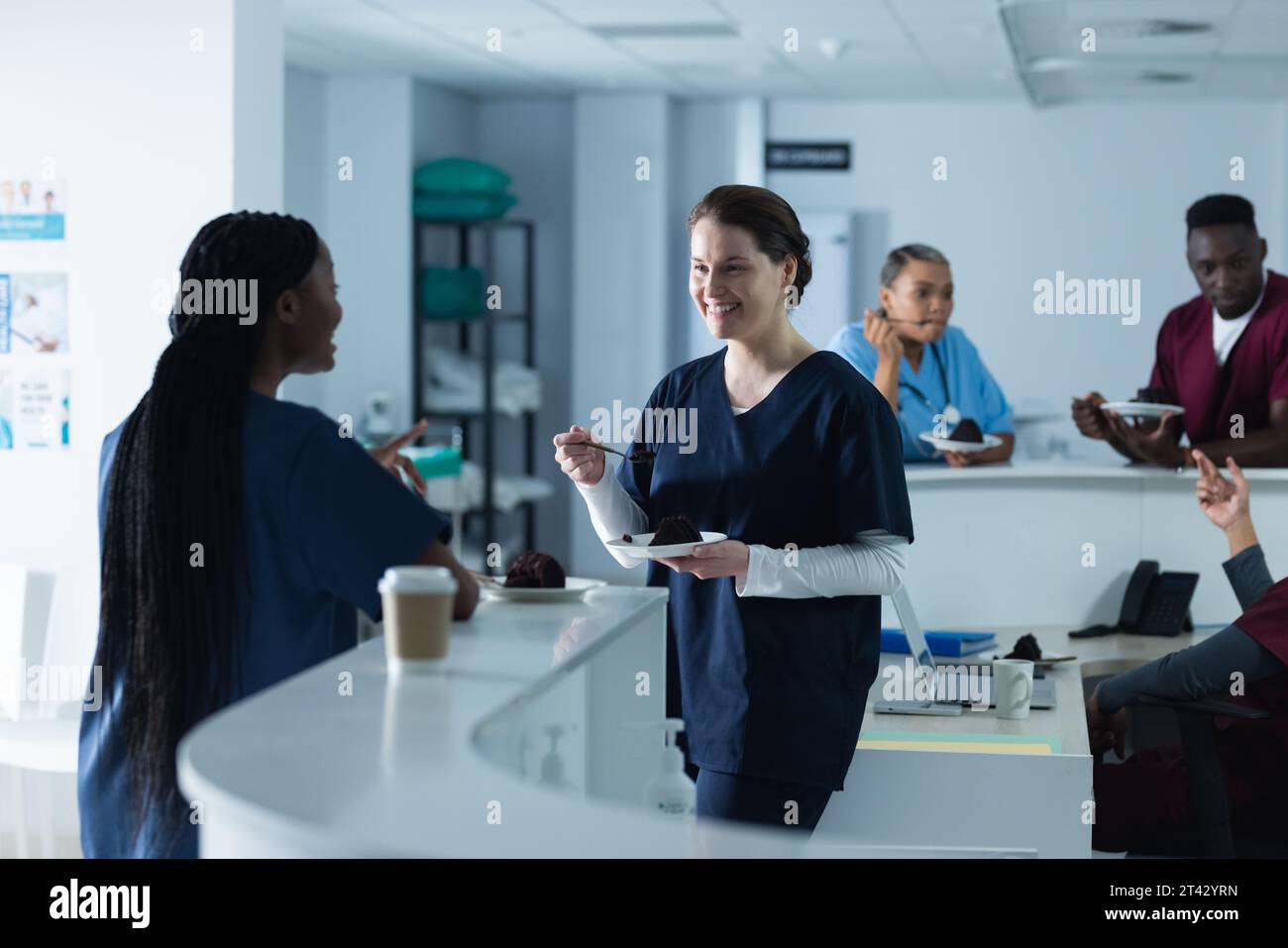 Happy diverse male and female doctors eating birthday cake at reception ...