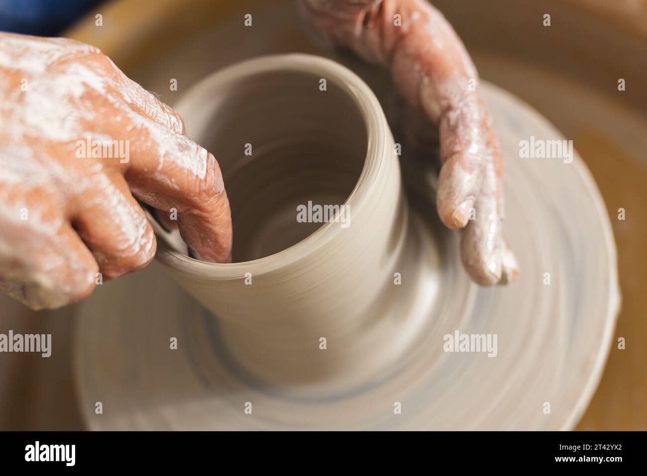 Hands of biracial senior potter with long beard using potter's wheel in ...
