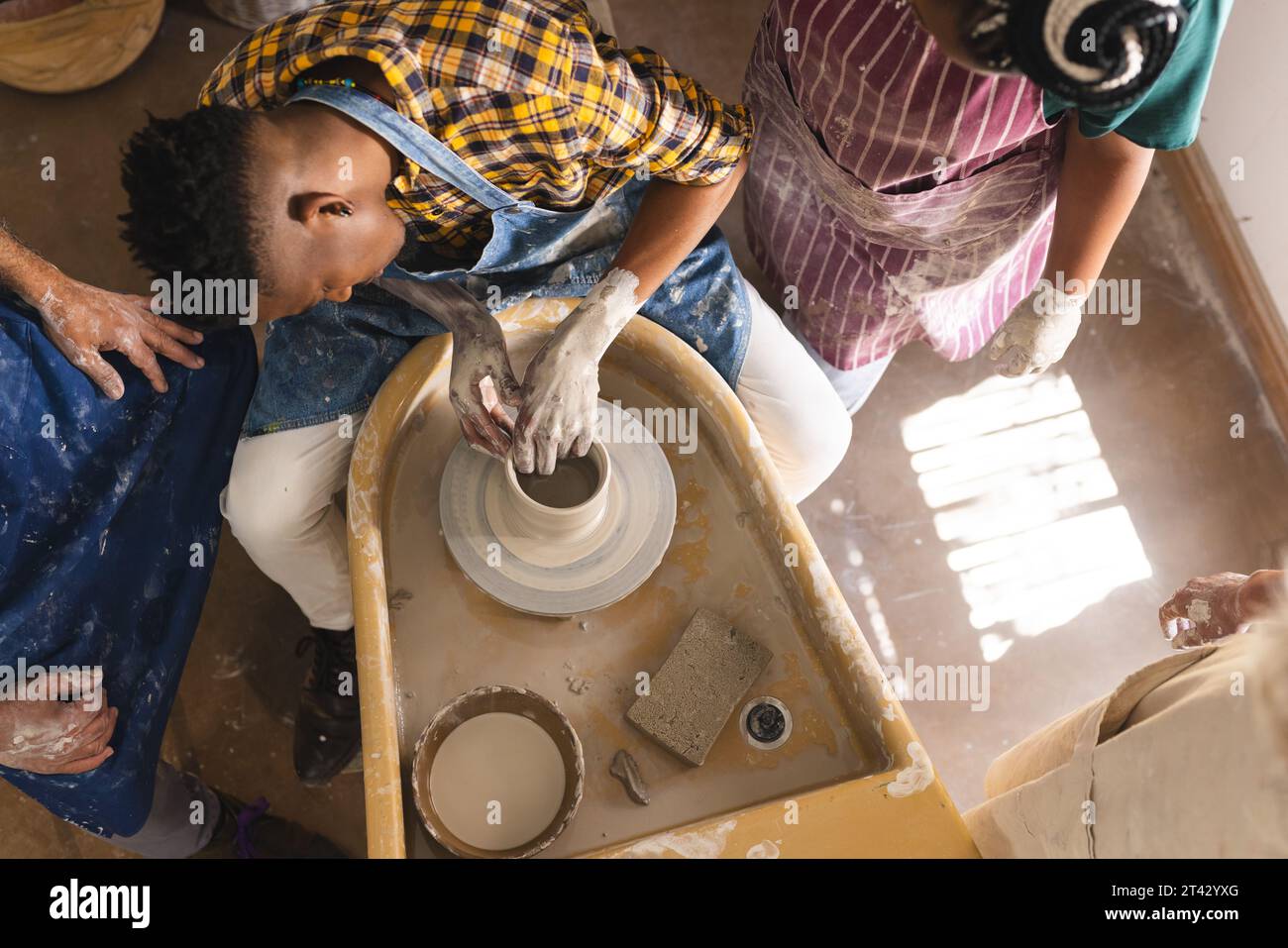 African american potter working on clay vase using potter's wheel in ...