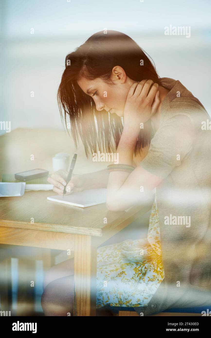 Woman, thinking and writing in notebook by desk, coffee shop and ...