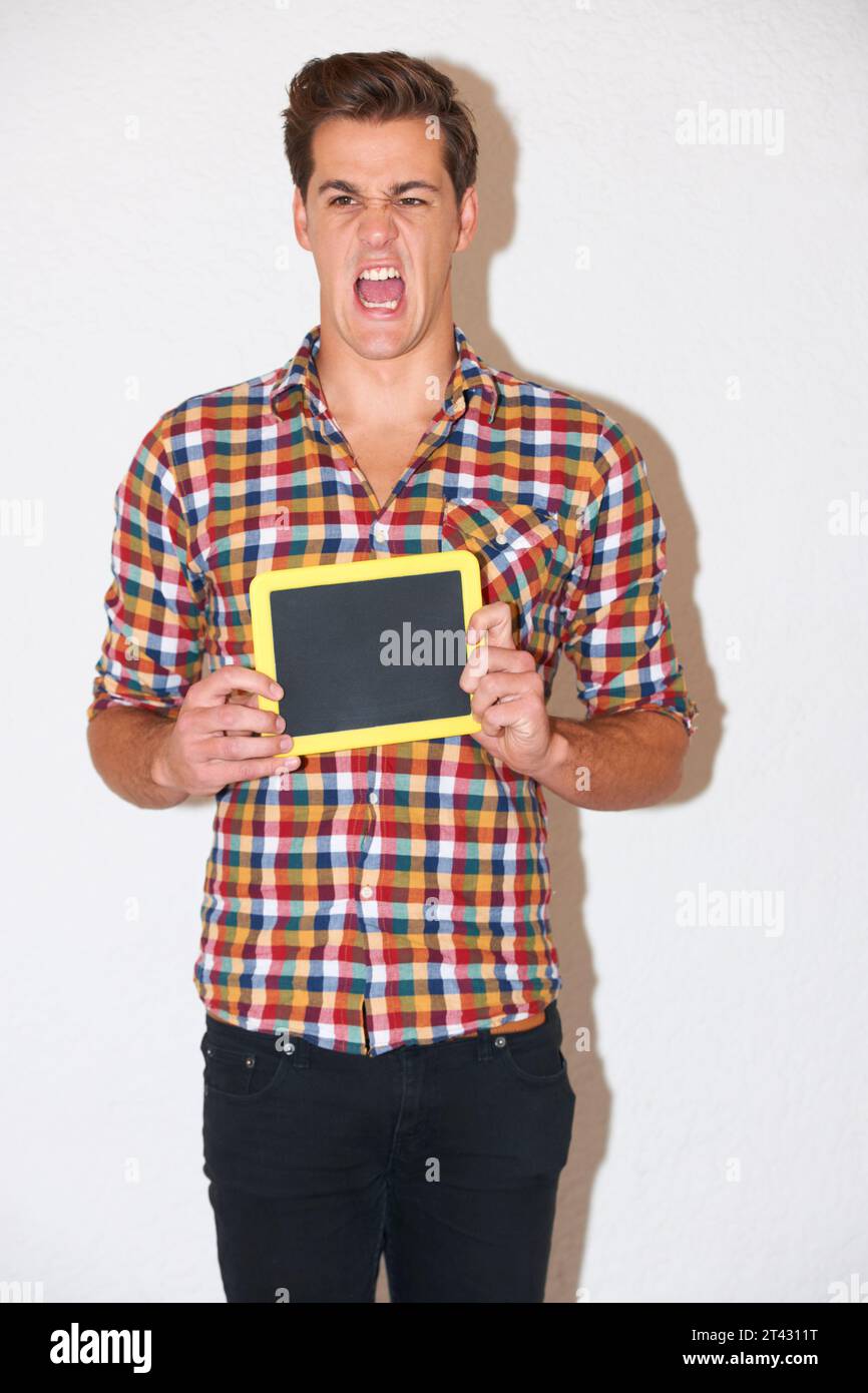 Screaming, angry and man with blackboard for education in studio ...