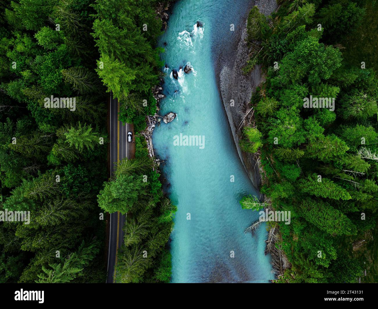 Aerial view of a straight road and river through a forest landscape ...