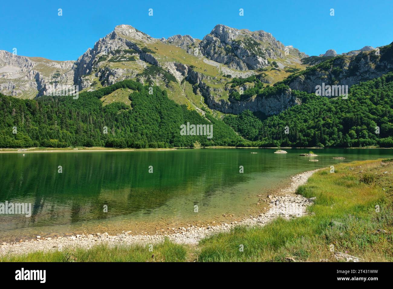 green water of lake in Montenegro below the peaks of mountains in ...