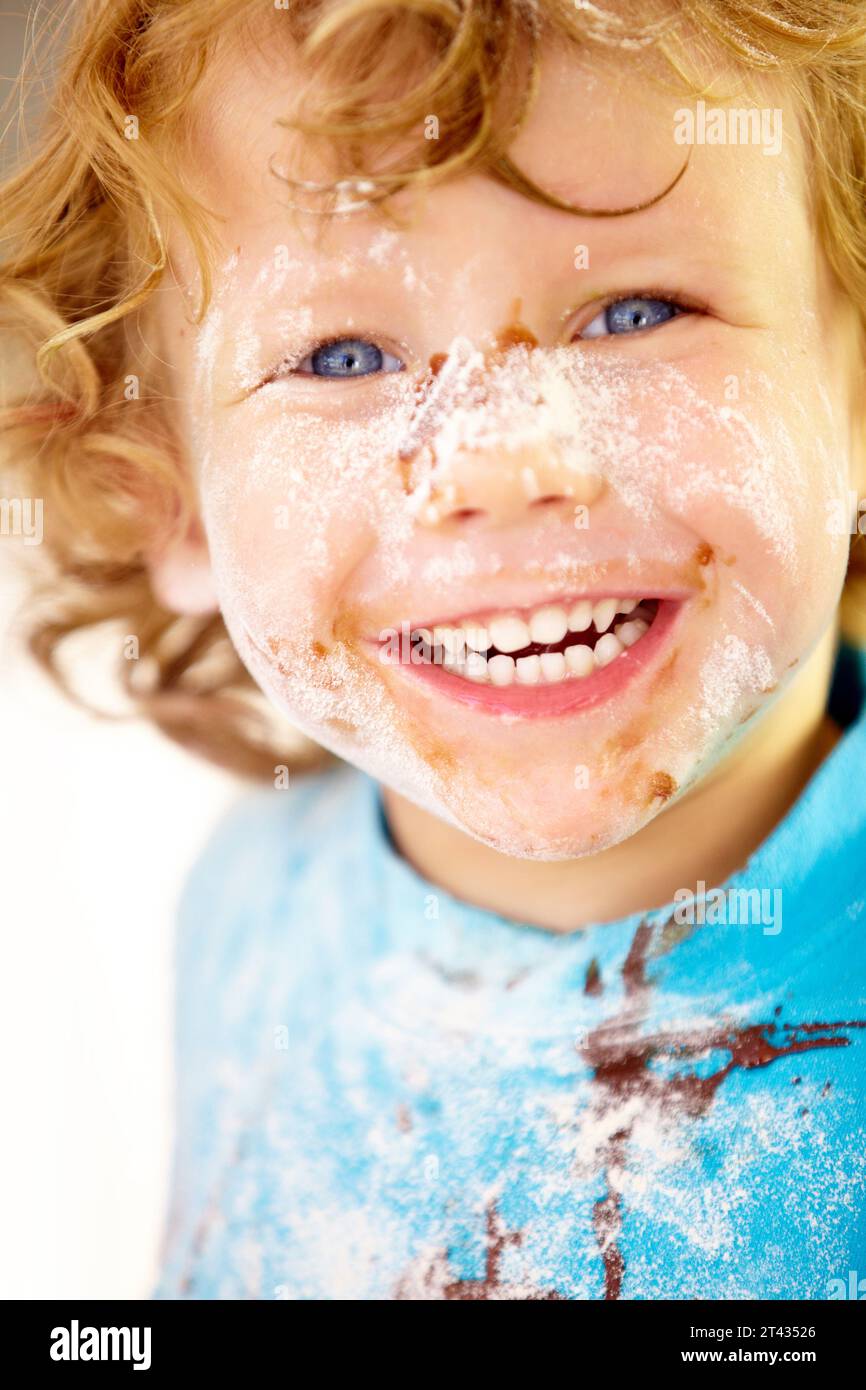 Portrait, mess and flour with a boy in the kitchen of his home ...