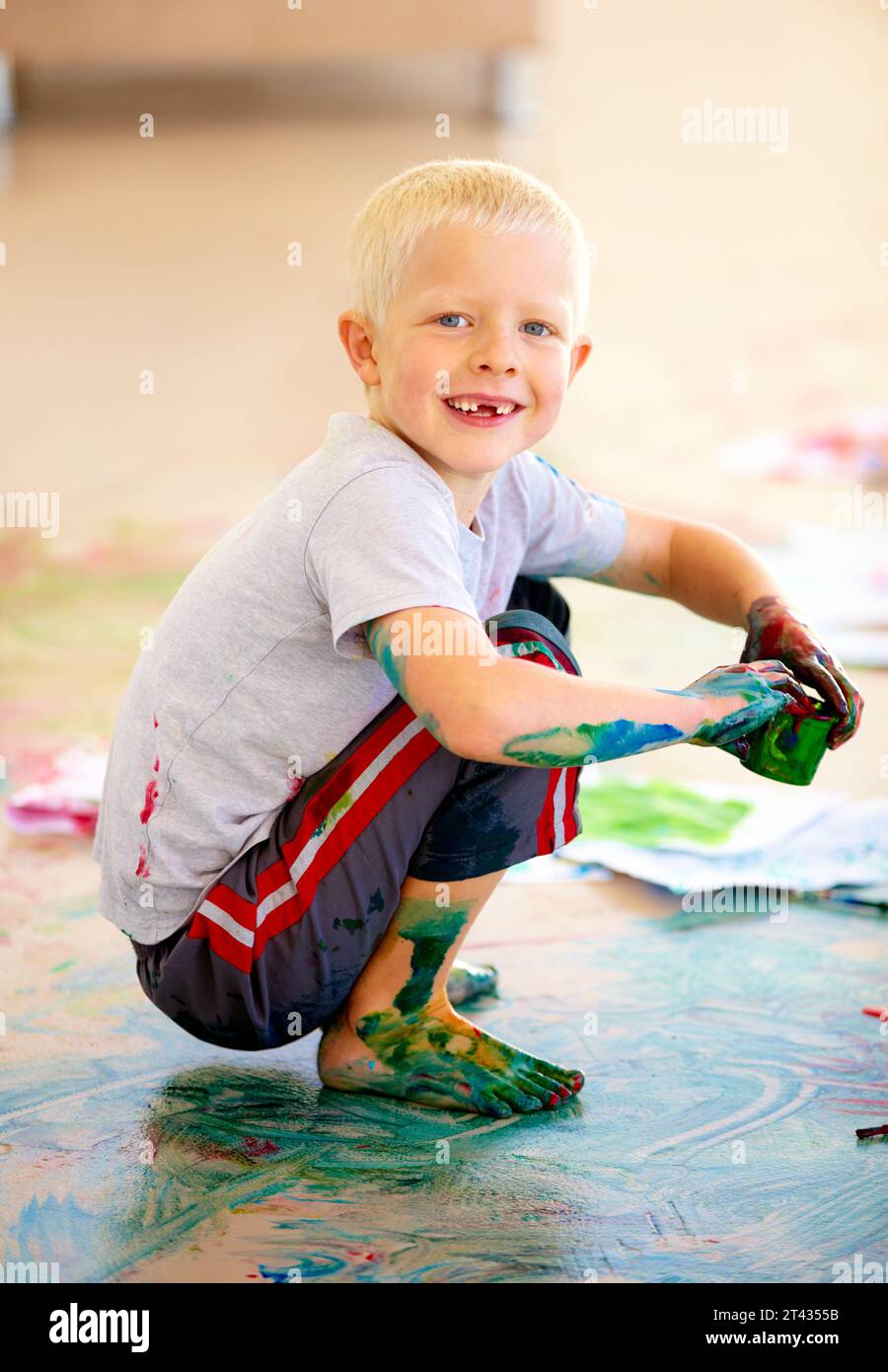 Portrait, smile and boy painting the floor in a studio for art ...