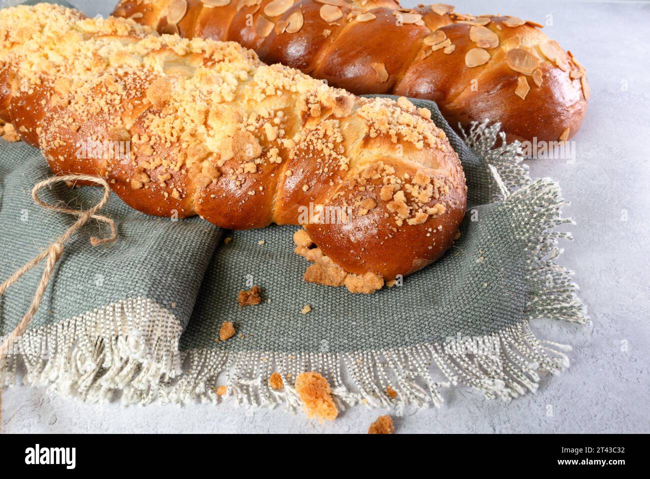 A close-up of two challah breads topped with almond and sweet crumbs on ...