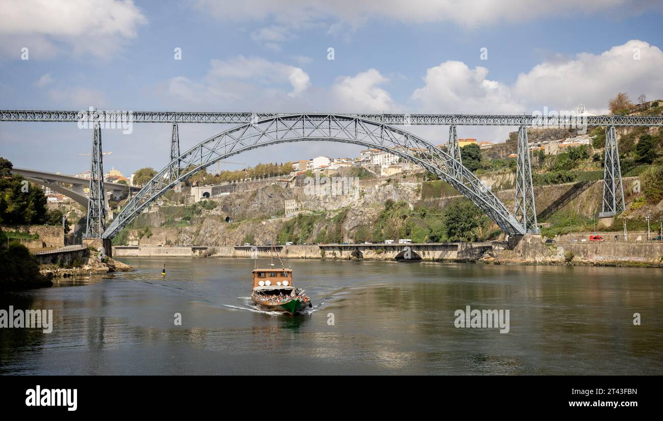 The Maria Pia bridge over the River Douro with Rabelo tour boat in ...