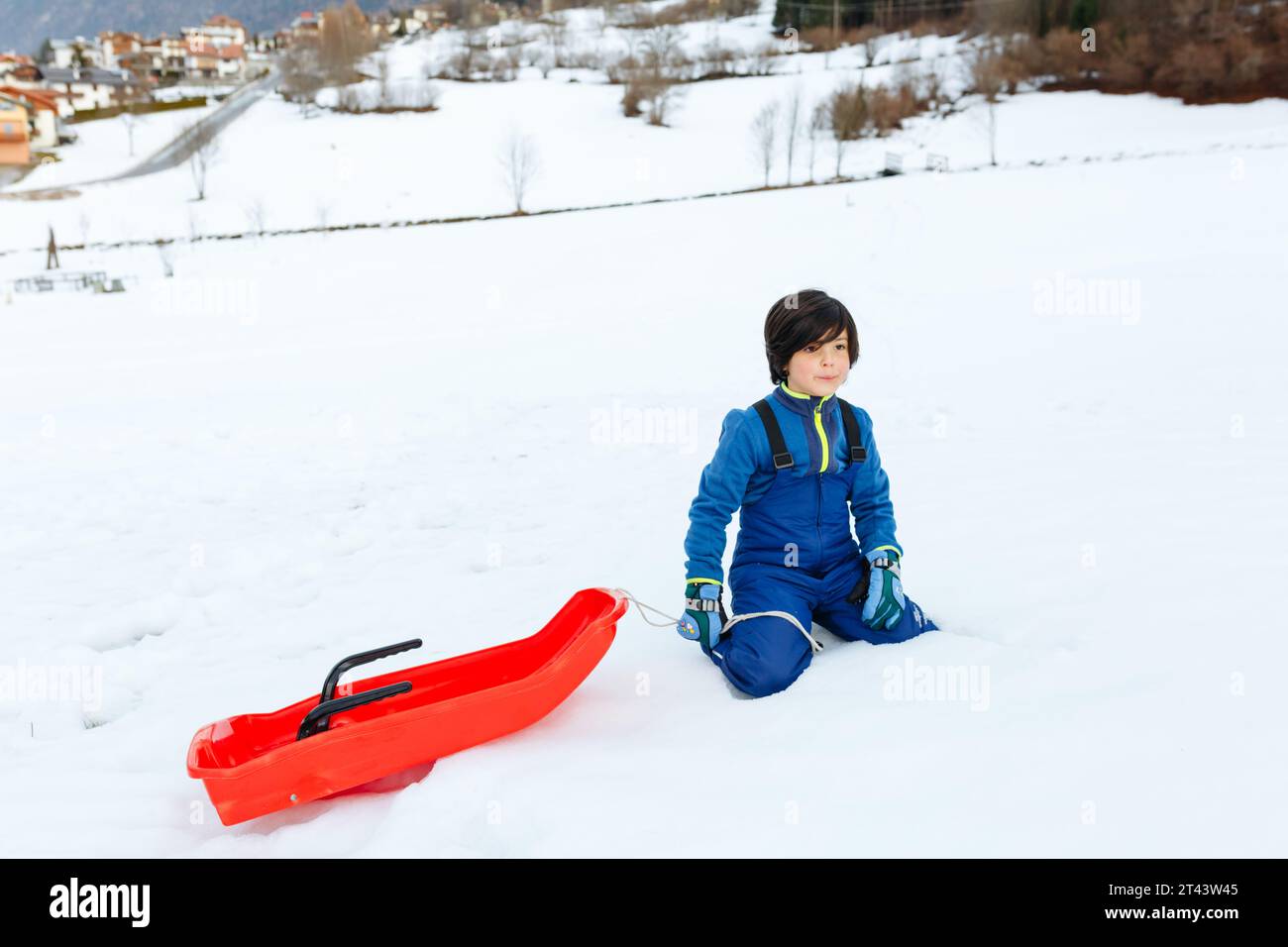 girl with short hair in blue winter clothes sitting tired on the snow ...