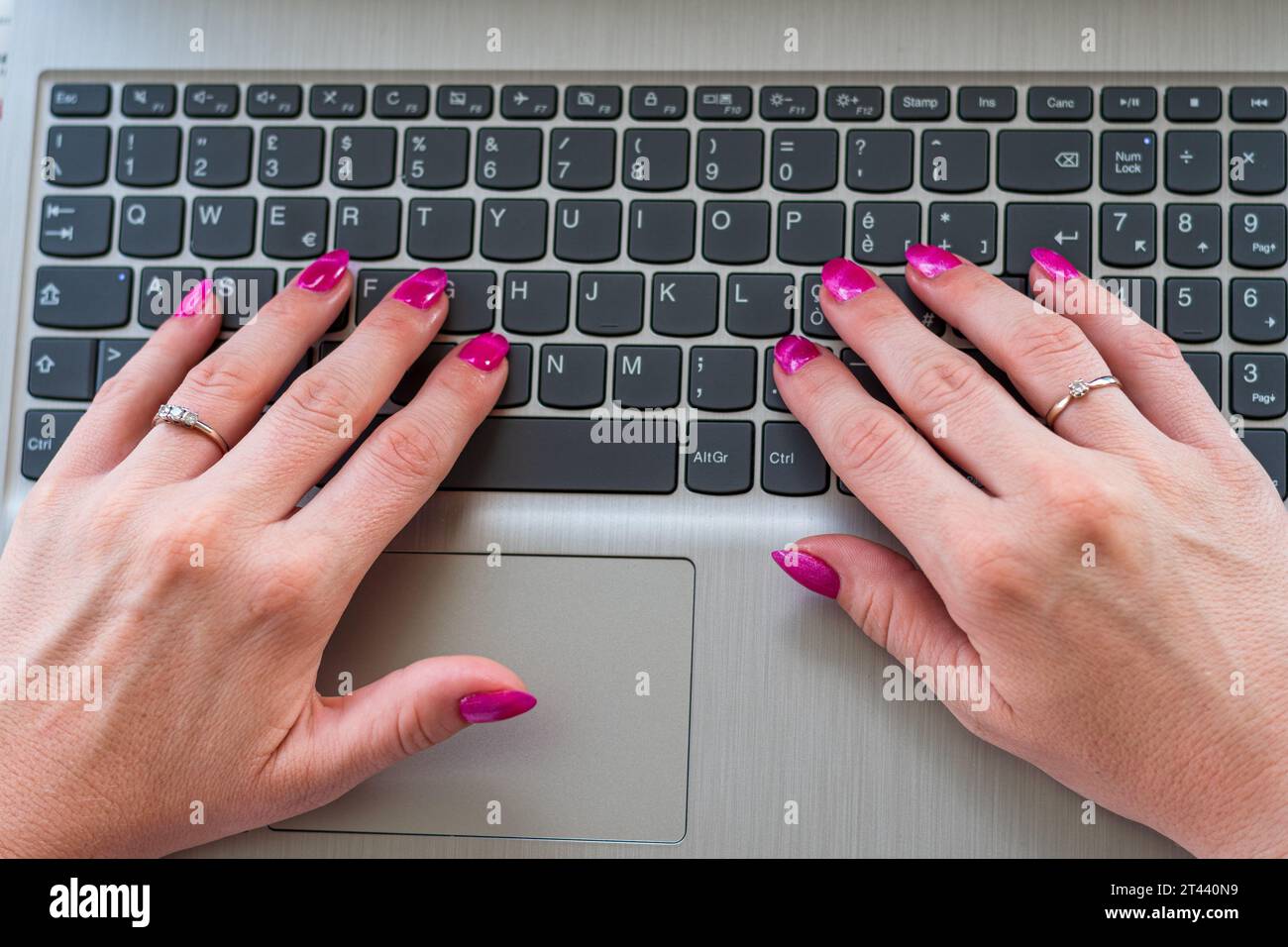 Woman using laptop. Close-up hands of a girl with purple nail polish ...