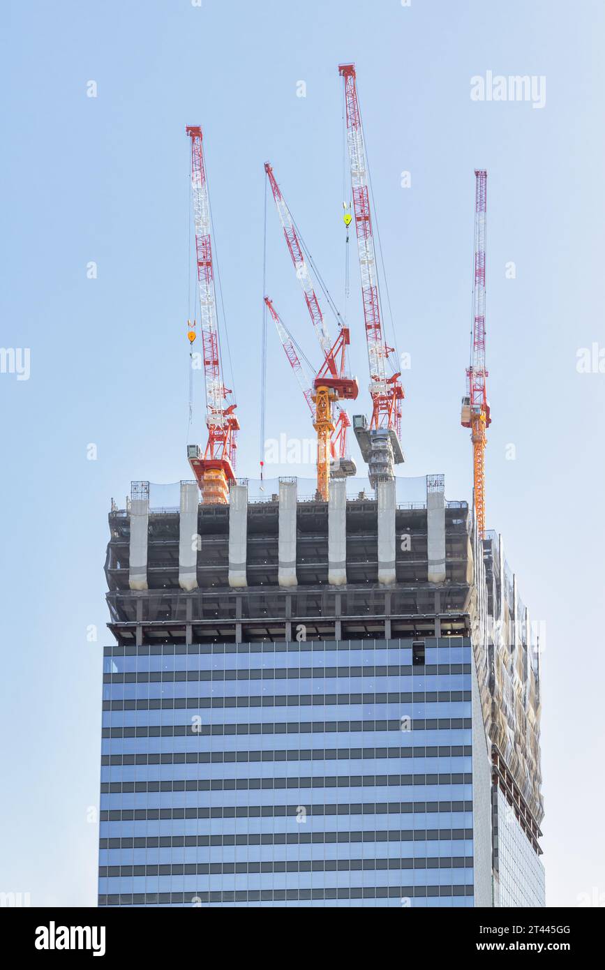 picture of a construction site of a skyscraper with cranes on the top ...