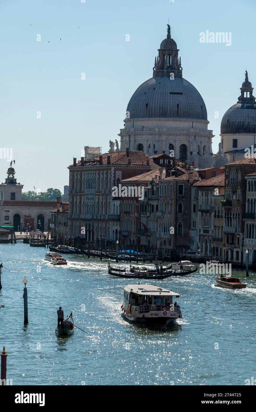 A busy boating scene of gondolas and other rivercraft near one of ...