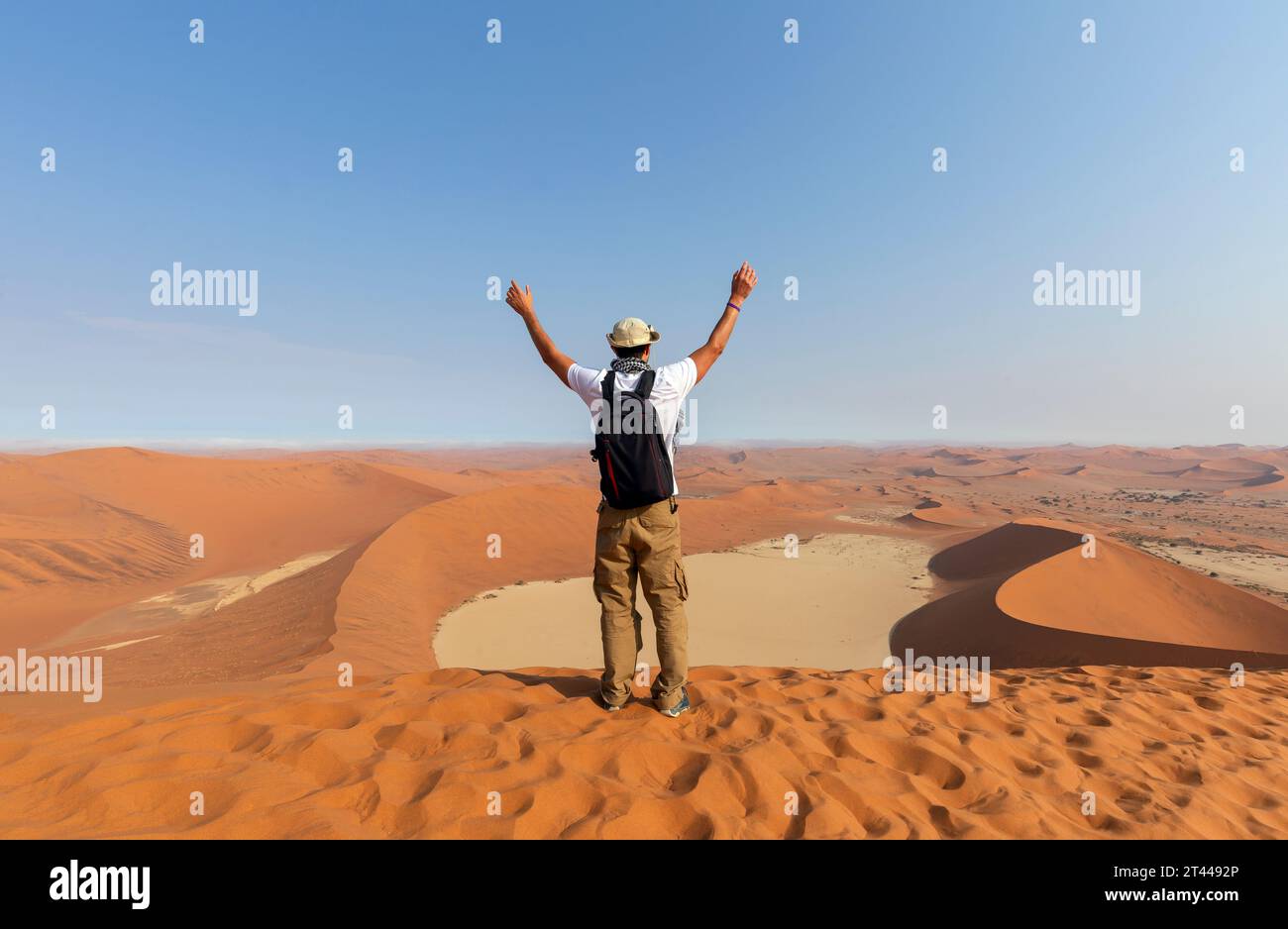 Happy male tourist with open arms on sand dunes in the Africa desert ...