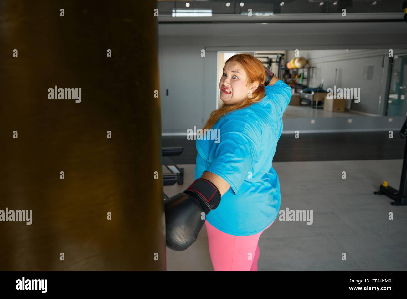Concentrated fat woman using boxing gloves doing punching exercises ...