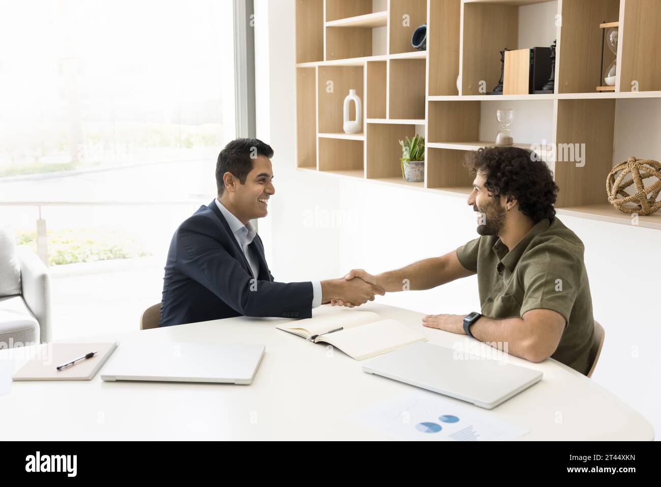Two cheerful Indian and Arab business partners giving greeting handshakes Stock Photo - Alamy