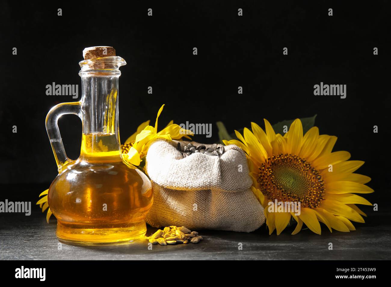 Decanter of sunflower oil and sack bag with seeds on black background ...