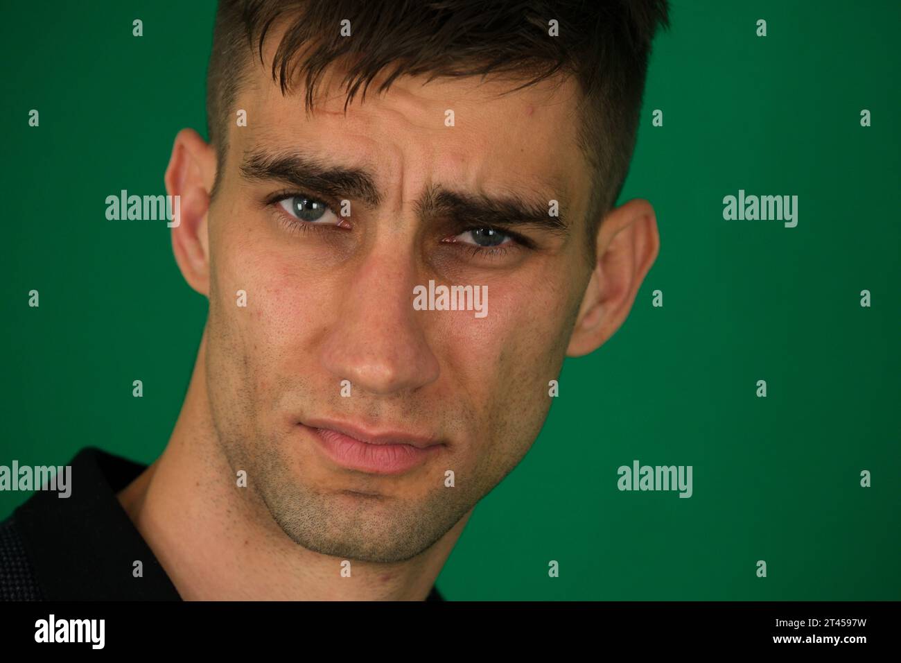 the anxious look of a handsome young man on a green background ...