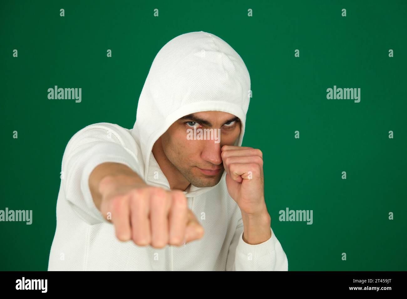 guy in a white hoodie on a green chromakey background hits the camera ...