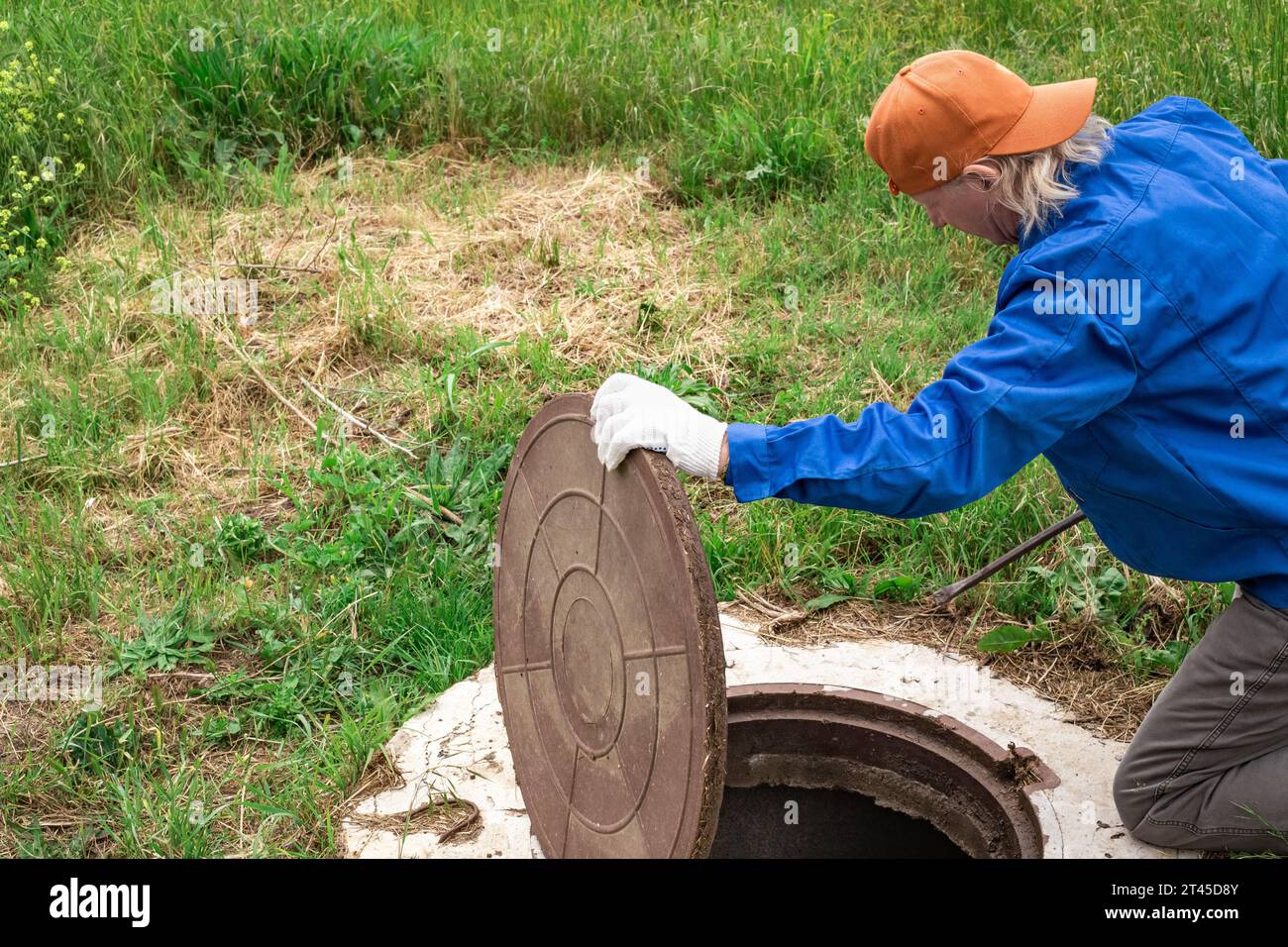 A plumber opens a manhole cover on a concrete well. Inspection and ...
