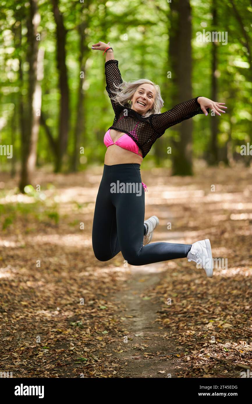 Young dancer woman making some dance moves in the forest, candid shot ...