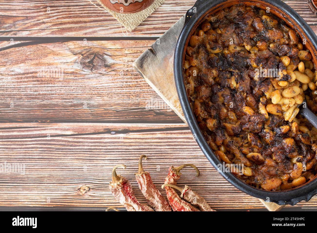 Baked bean soup in a clay dish on a wooden table with copy space. Top ...