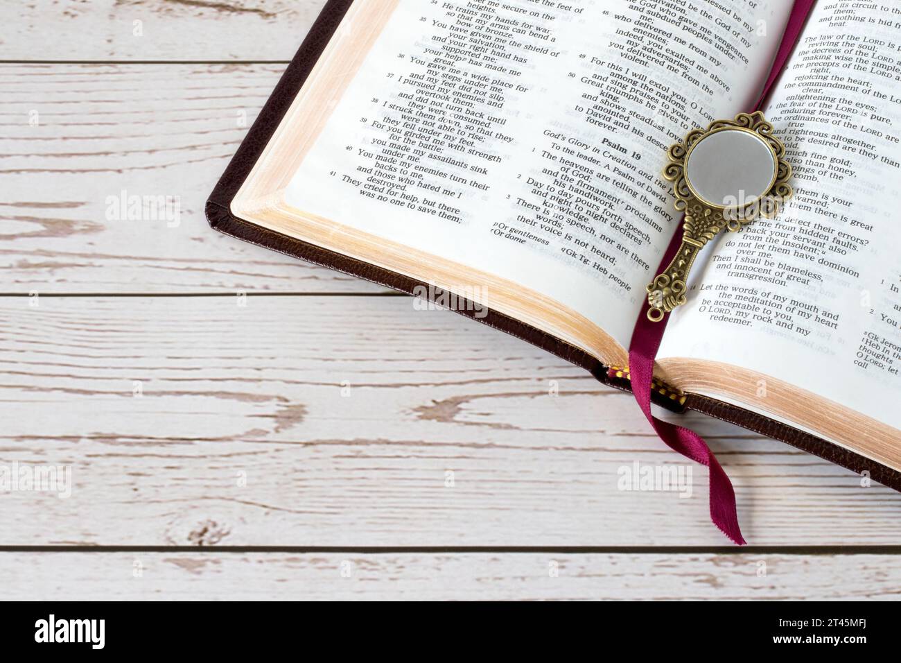 Open holy bible book and antique golden mirror on wooden table. Copy ...