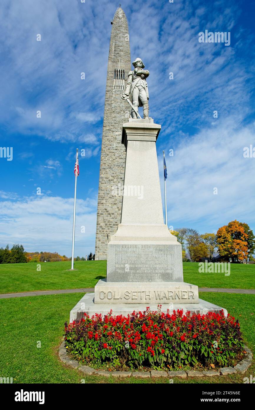 1911 granite statue of Colonel Seth Warner before stone obelisk under cloud swept blue sky ...