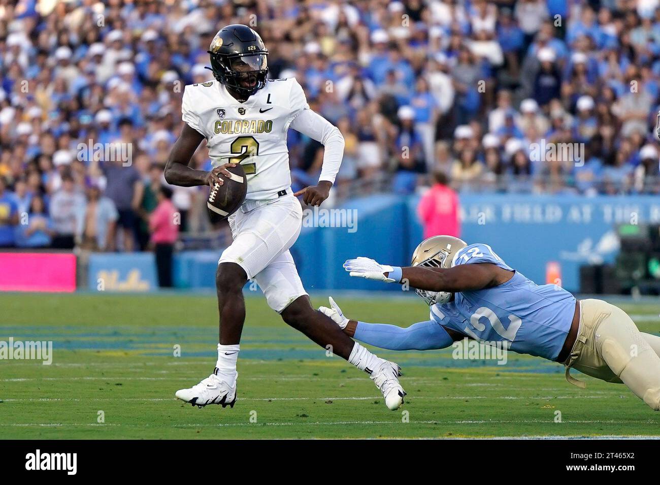 Colorado quarterback Shedeur Sanders, left, escapes a tackle by UCLA ...
