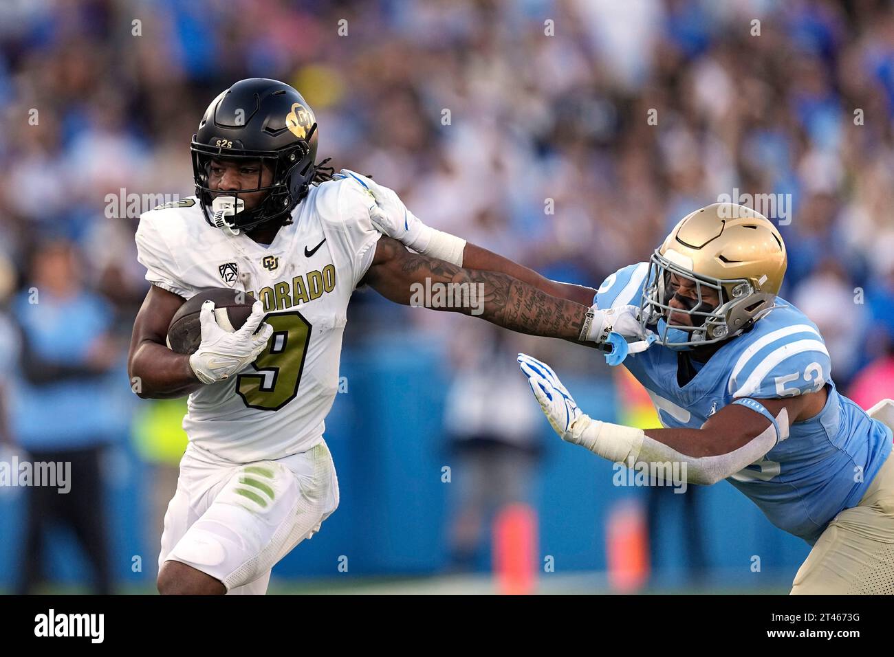Colorado running back Anthony Hankerson, left, fends off UCLA ...