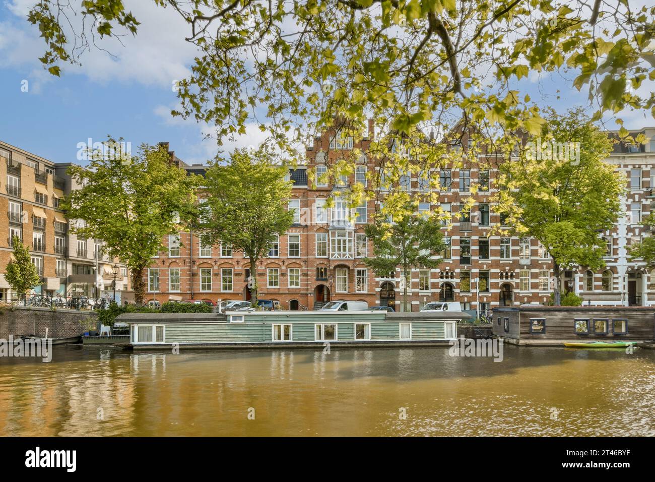 some buildings on the side of a body of water with trees and boats in ...
