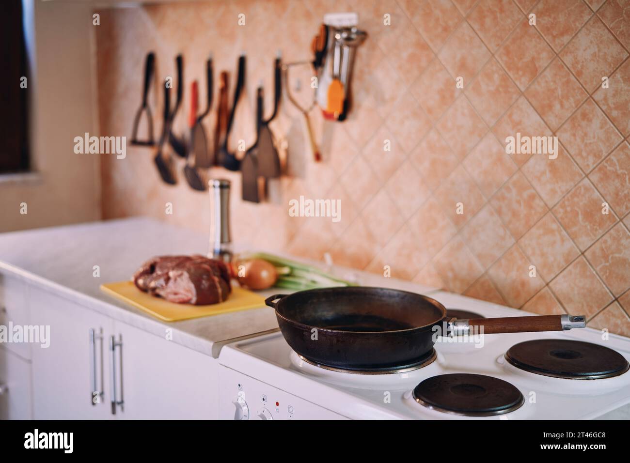 Frying pan stands on the stove against the background of a raw ...