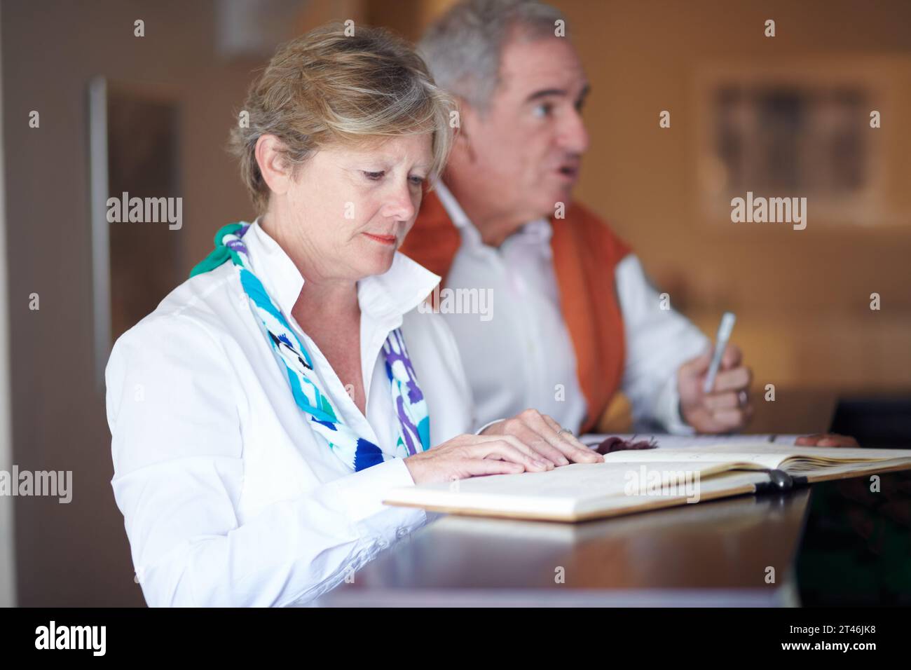 Travel, hotel and elderly couple by reception to check in desk for ...