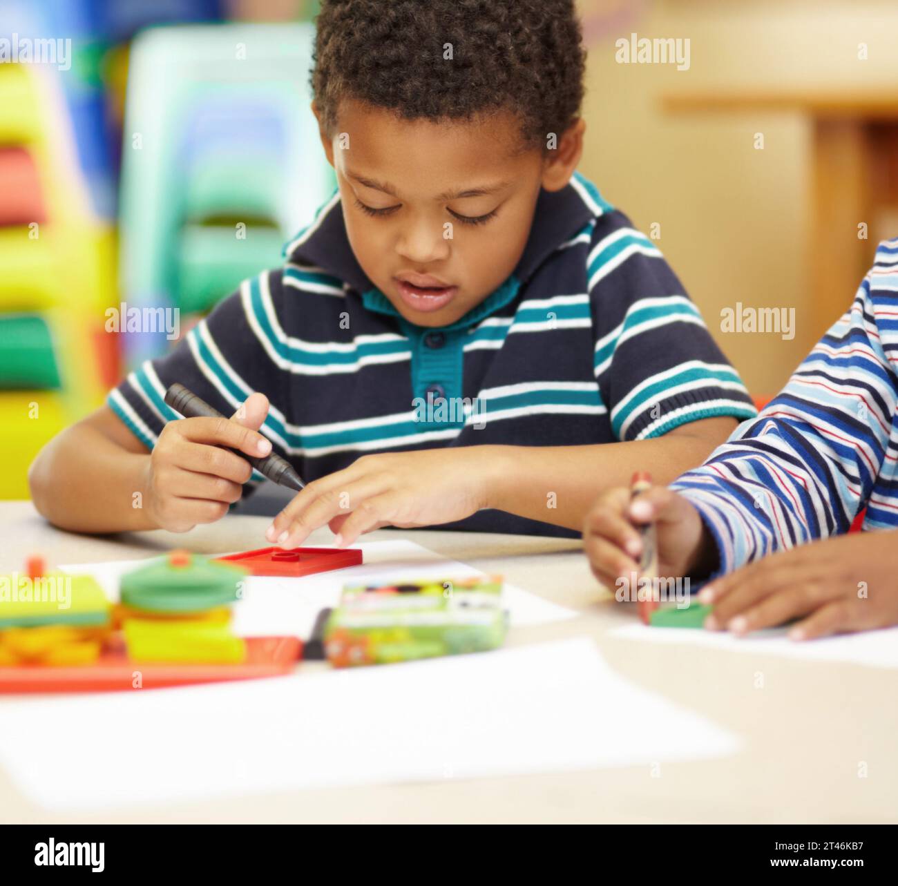 African boy, learning and writing at kindergarten with paper, crayon ...