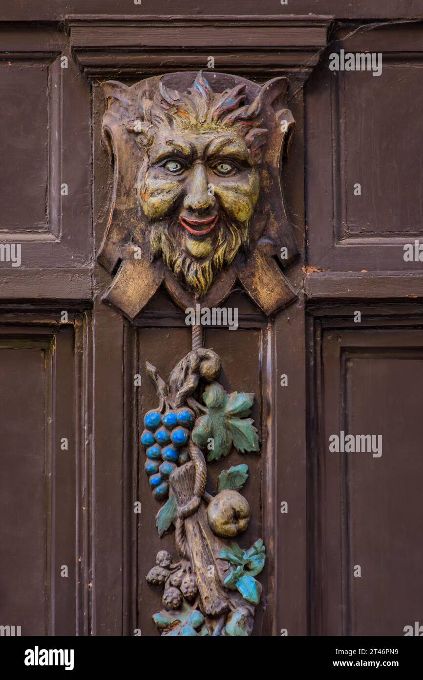 Carved wooden Bacchus face with a grapevine on an ancient traditional ...