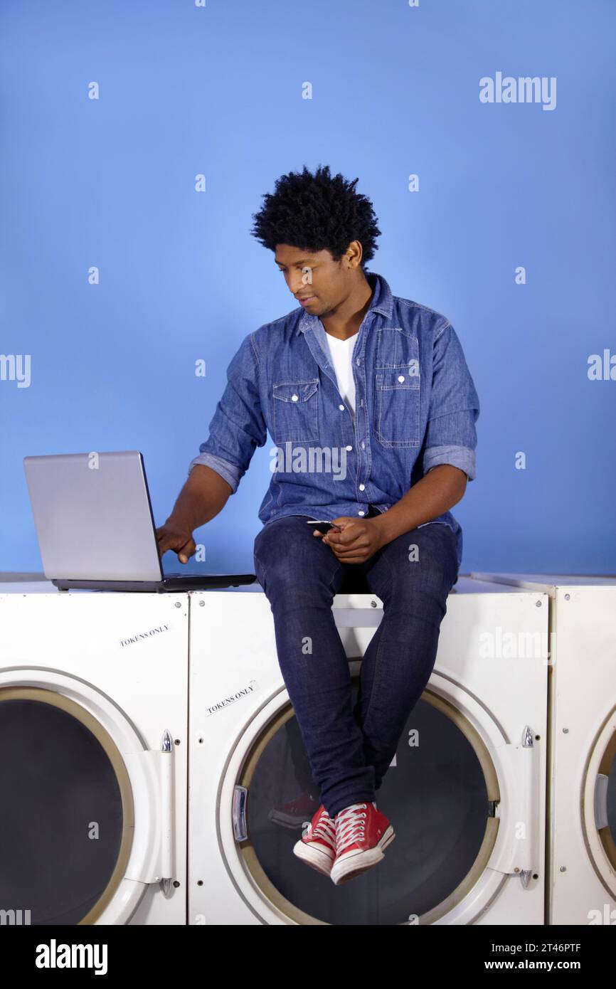 Washing machine, laptop and phone of a black man for laundromat ...