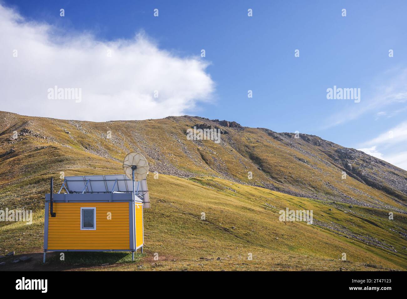 A lodge in the mountains with an antenna and solar panels. Green energy ...
