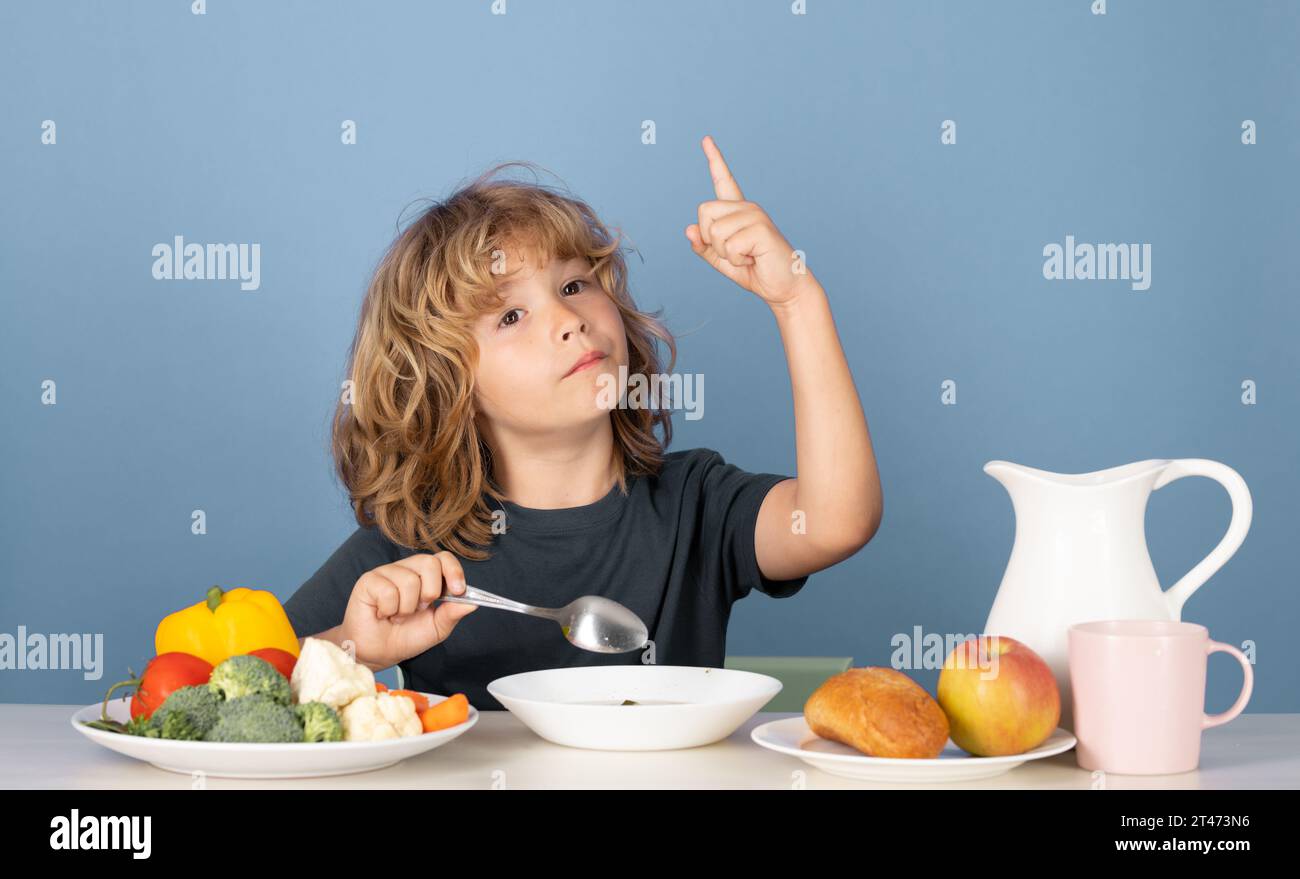 Child eating soup. Cute little child having lunch sitting at the table ...