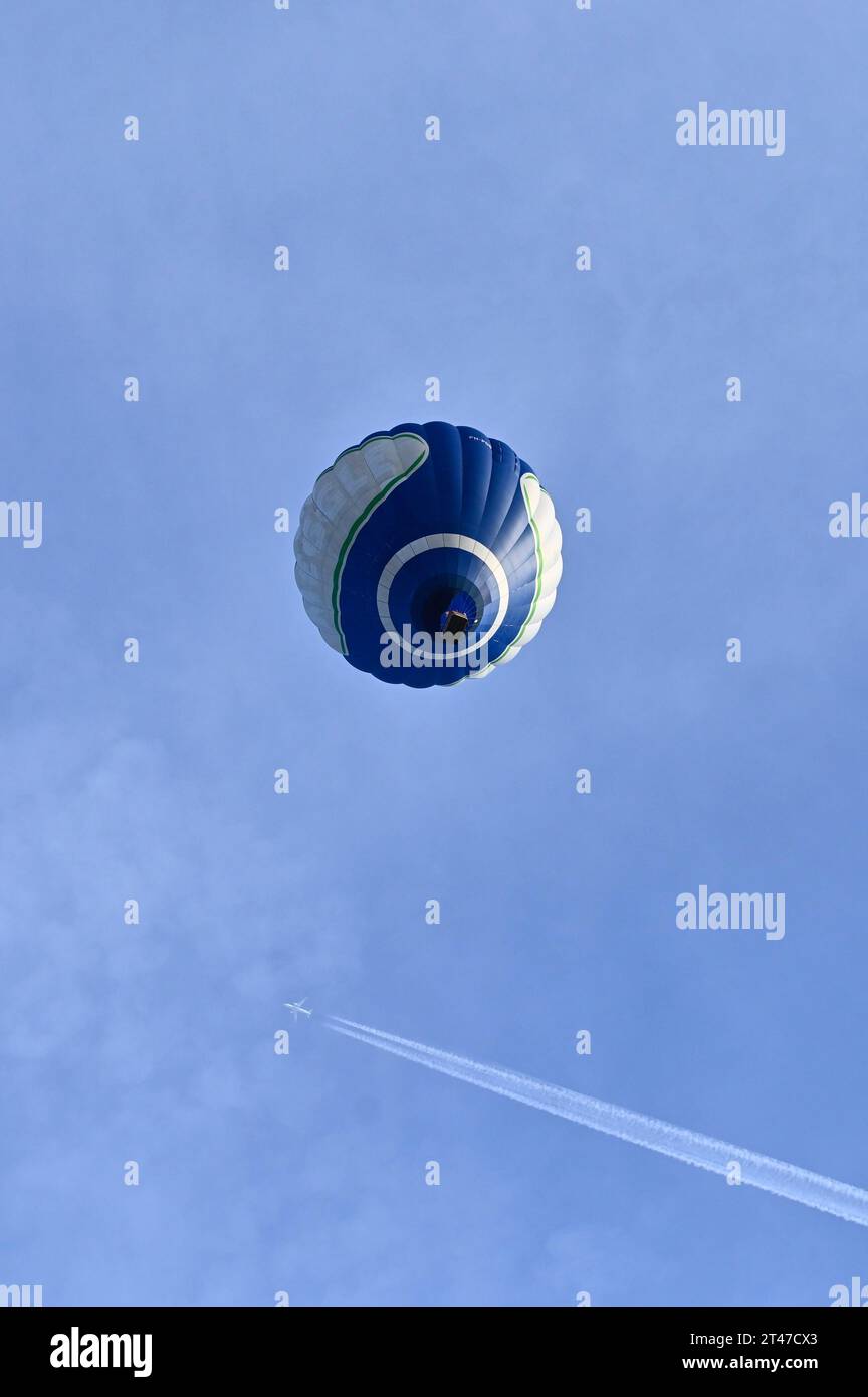 Blue hot air balloon in a sky blue sky seen from below, while a passing ...