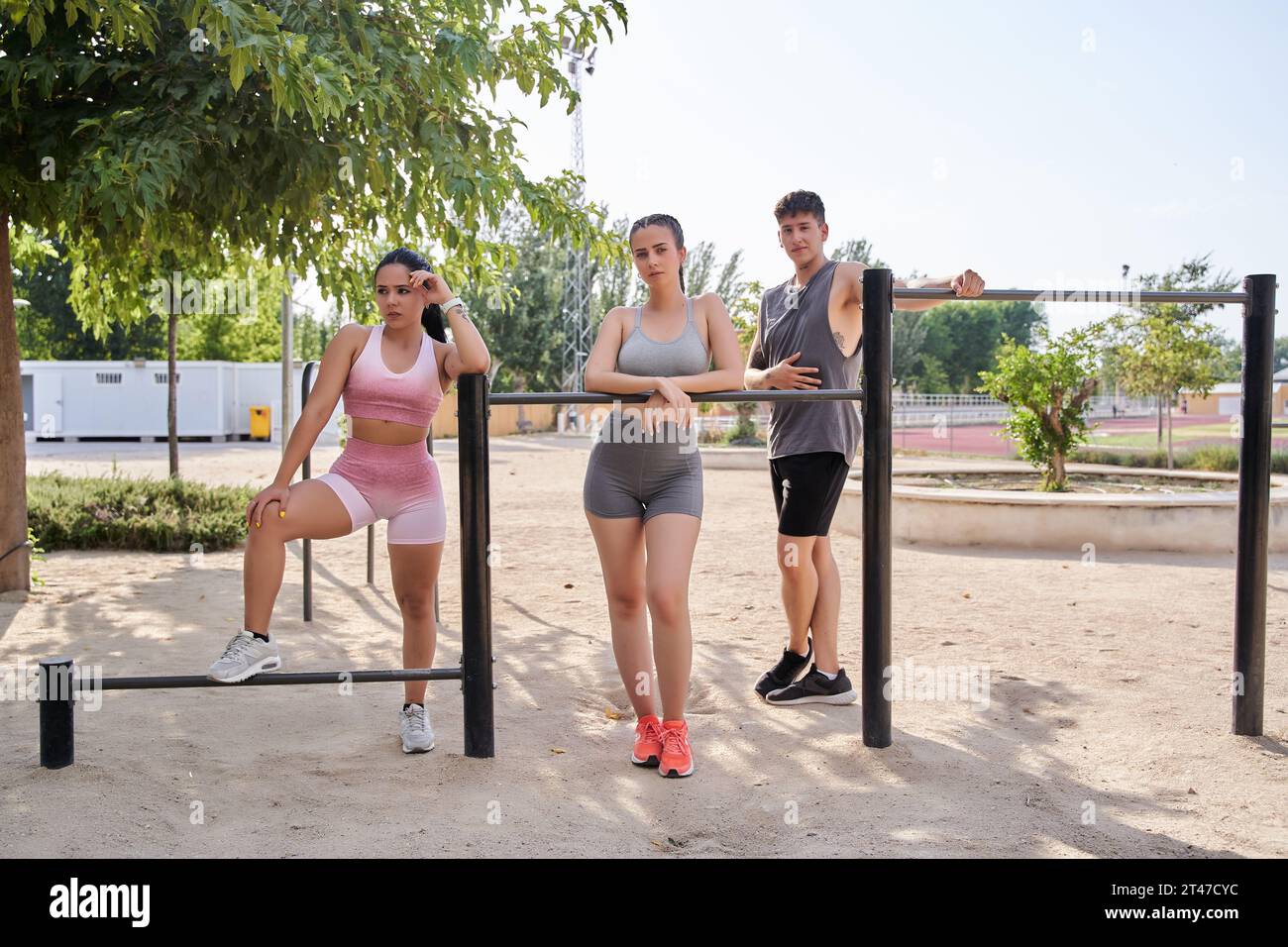 Full-length of three young sporty people standing and posing outdoors ...