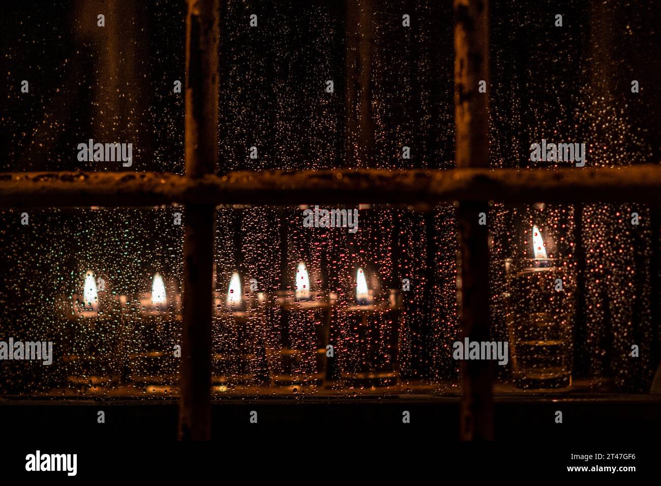 Golden glow of a Hanukkah menorah with oil lights burning in a window ...