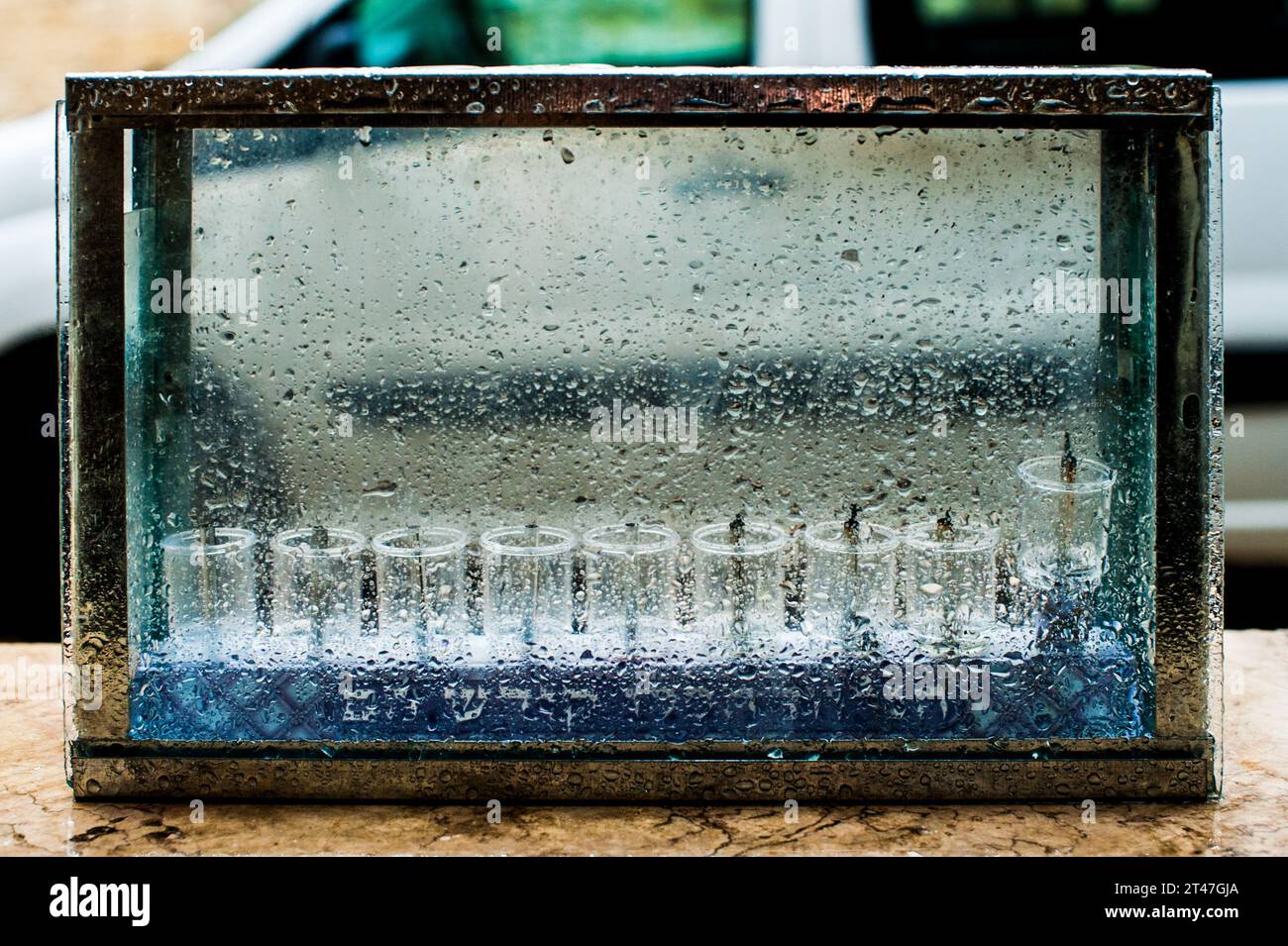 A glass housing protects unlit glass vials and wicks used to celebrate ...