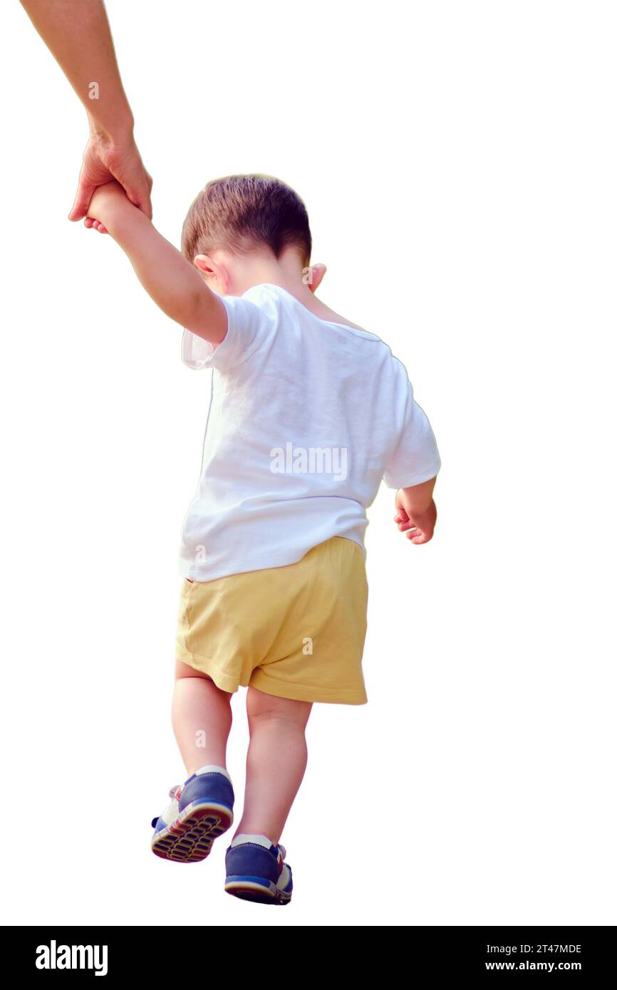Baby takes steps holding a mother woman by the hand along a path in ...
