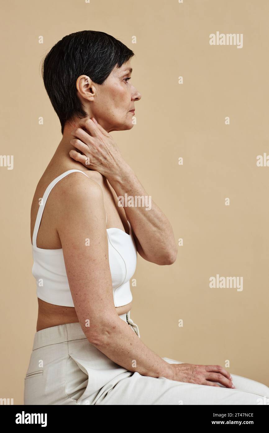 Minimal side view of adult woman scratching neck against neutral ...