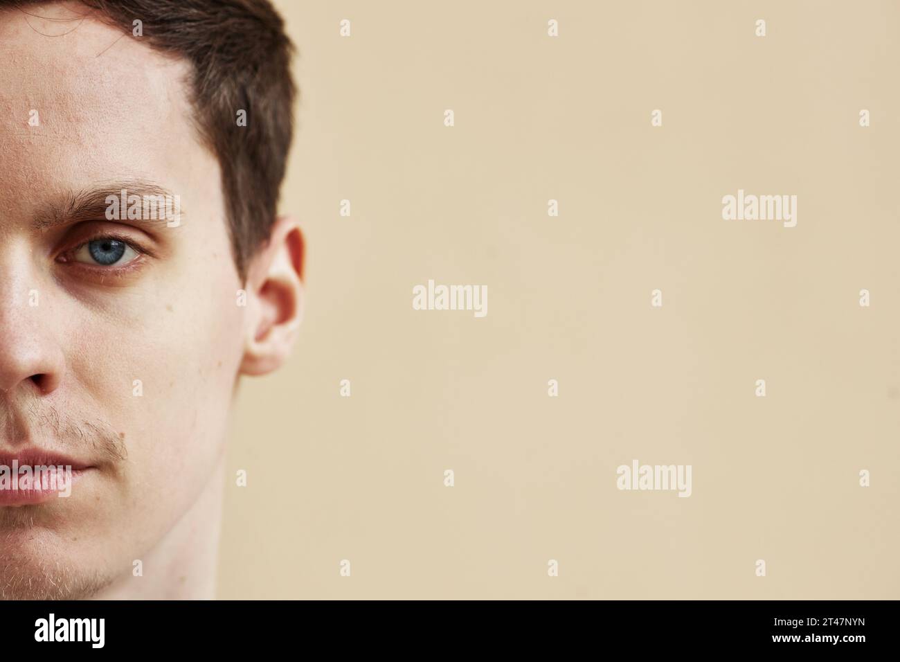 Half portrait of young man with striking blue eyes against neutral ...