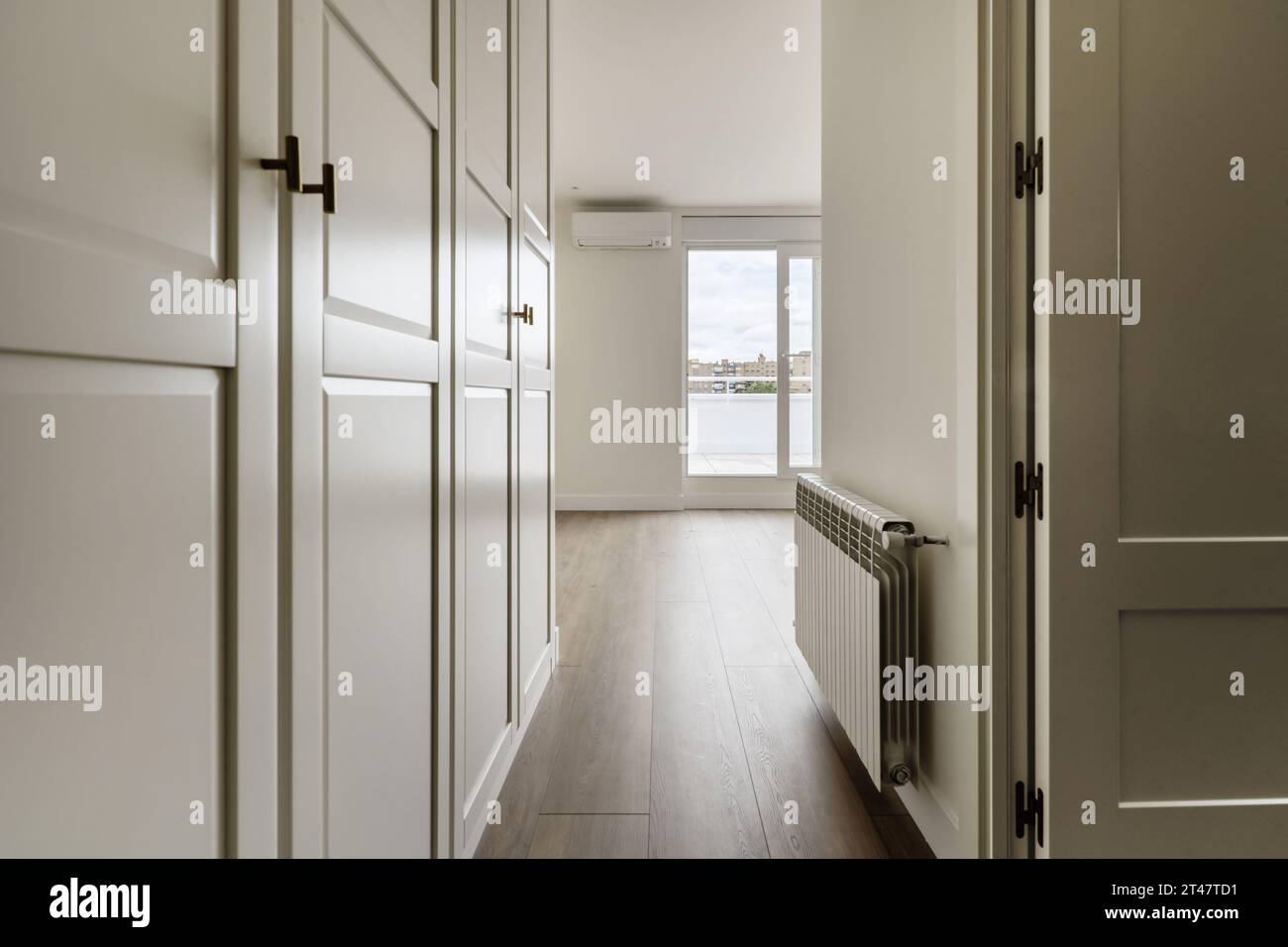 Corridor leading to a bedroom with a custom-made wardrobe on one side ...