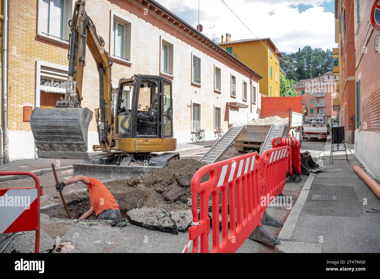 Construction Area with Operator digging with red safety barriers and ...