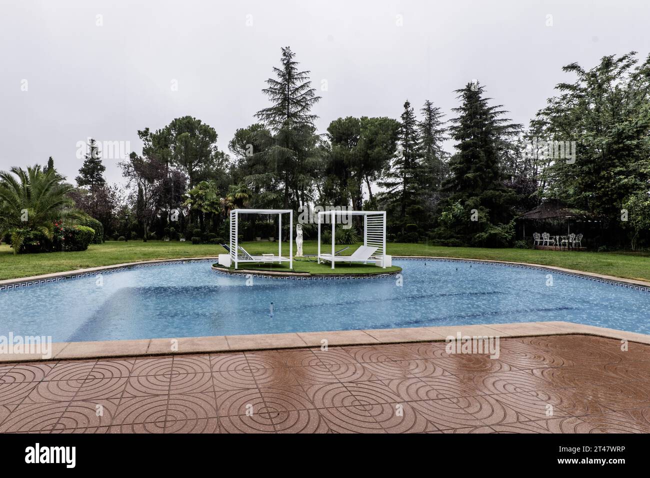 Large central island swimming pool with four poster beds Stock Photo ...