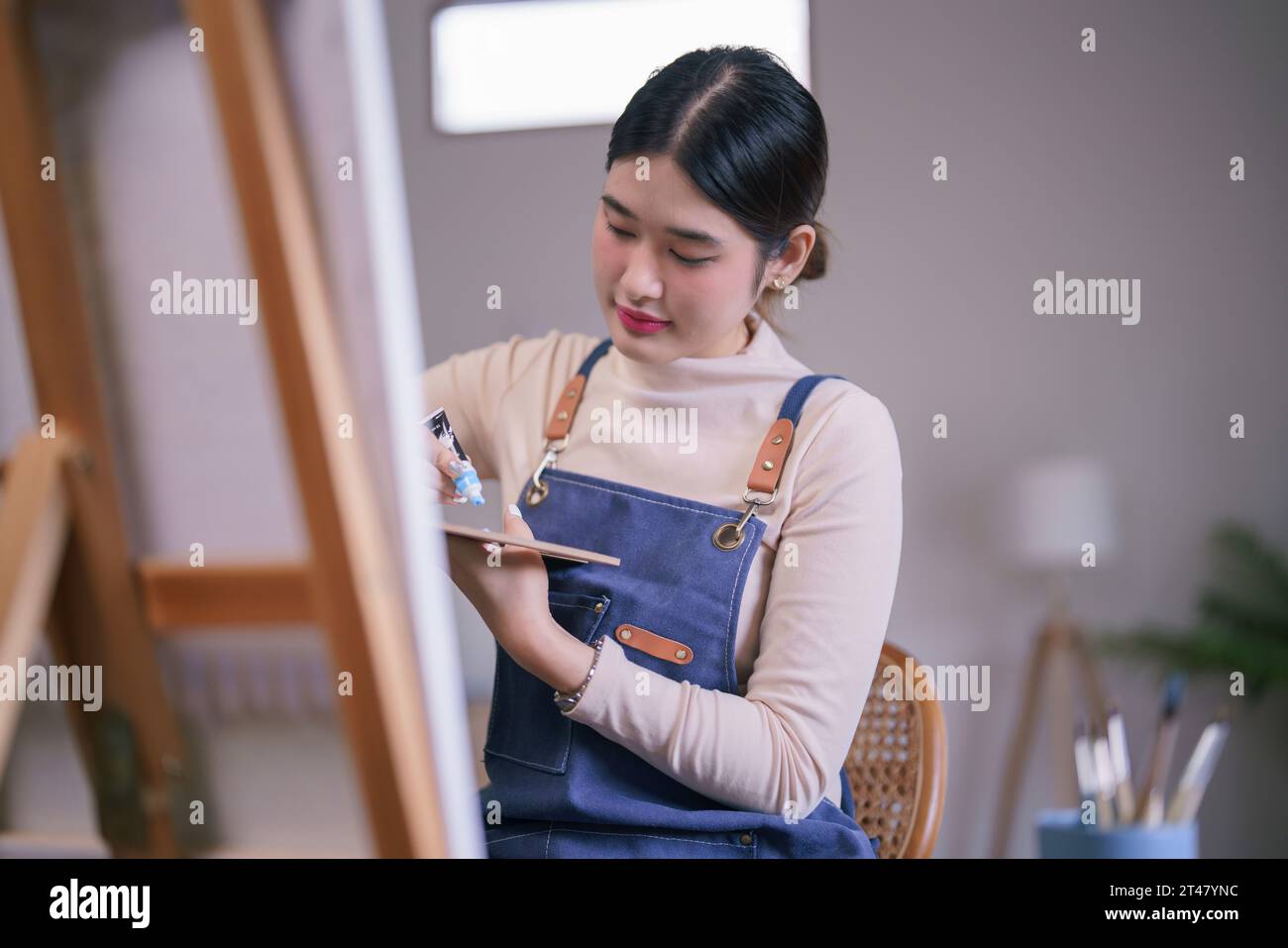 Young asian female artist squeeze color out of tube on color palette ...