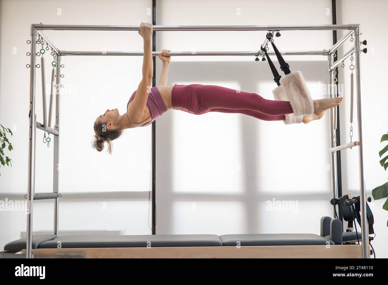 A caucasian woman is engaged in Pilates on a reformer simulator ...
