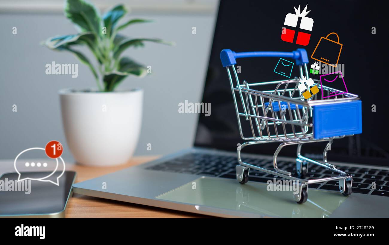 Shopping cart and gift box icons placed on laptop computer represent ...