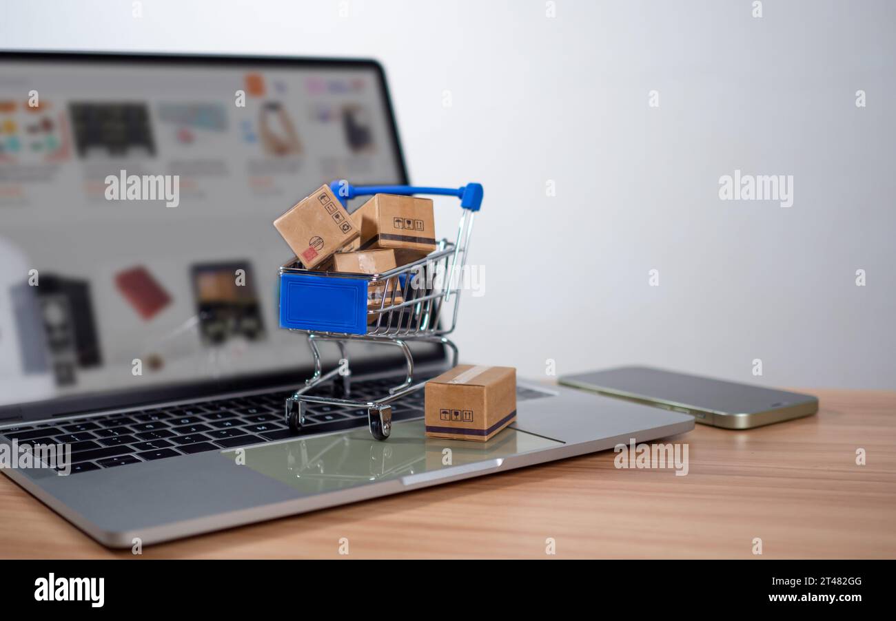 Shopping cart and product boxes placed on laptop computer represent ...